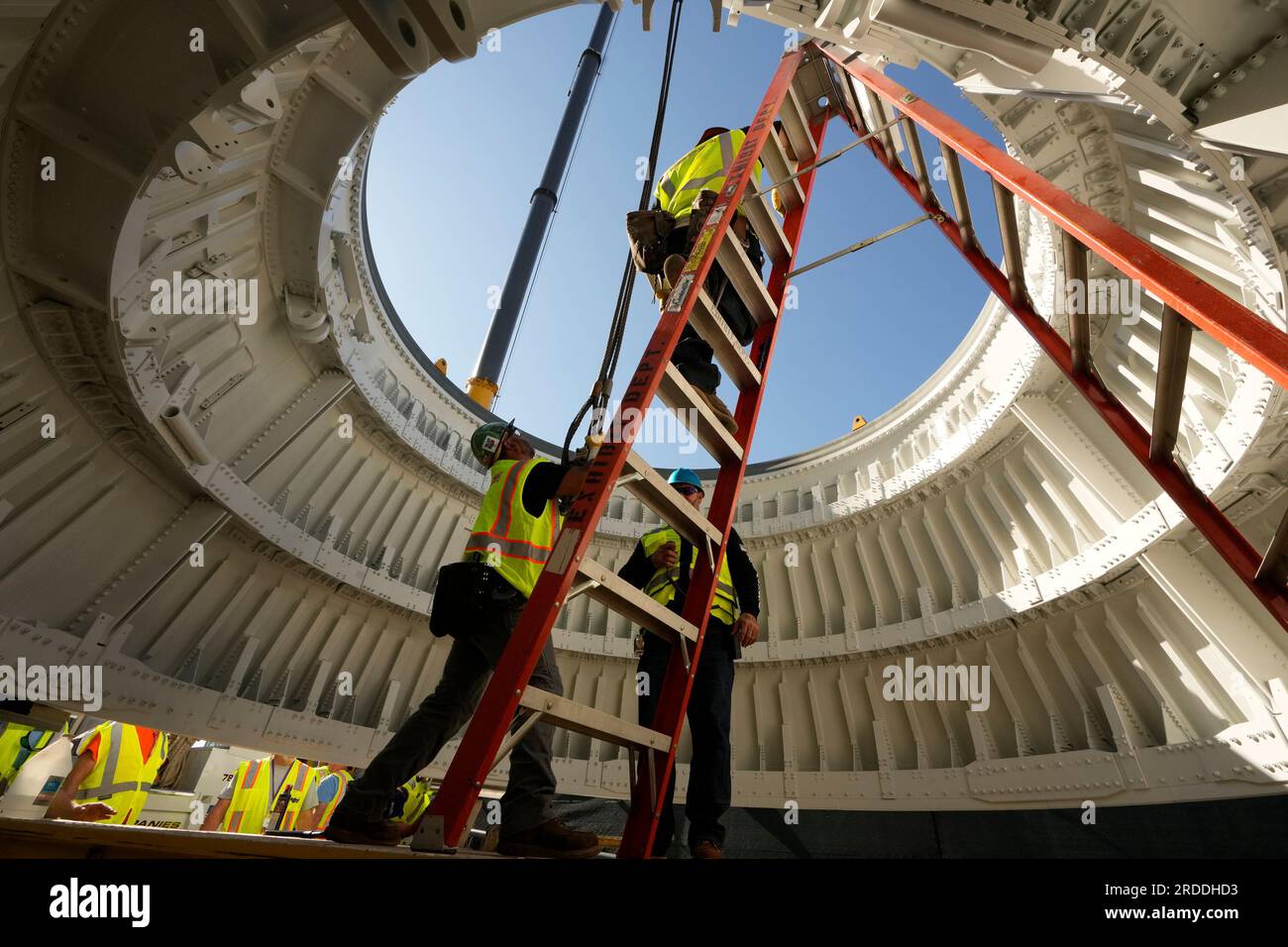 Technicians attach specialized lifting lugs to the top ring of the ...