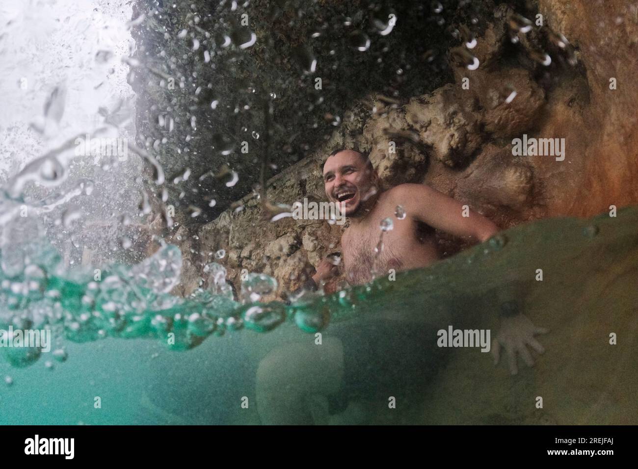 FILE - A young man cools off under a waterfall on a cloudy day with ...