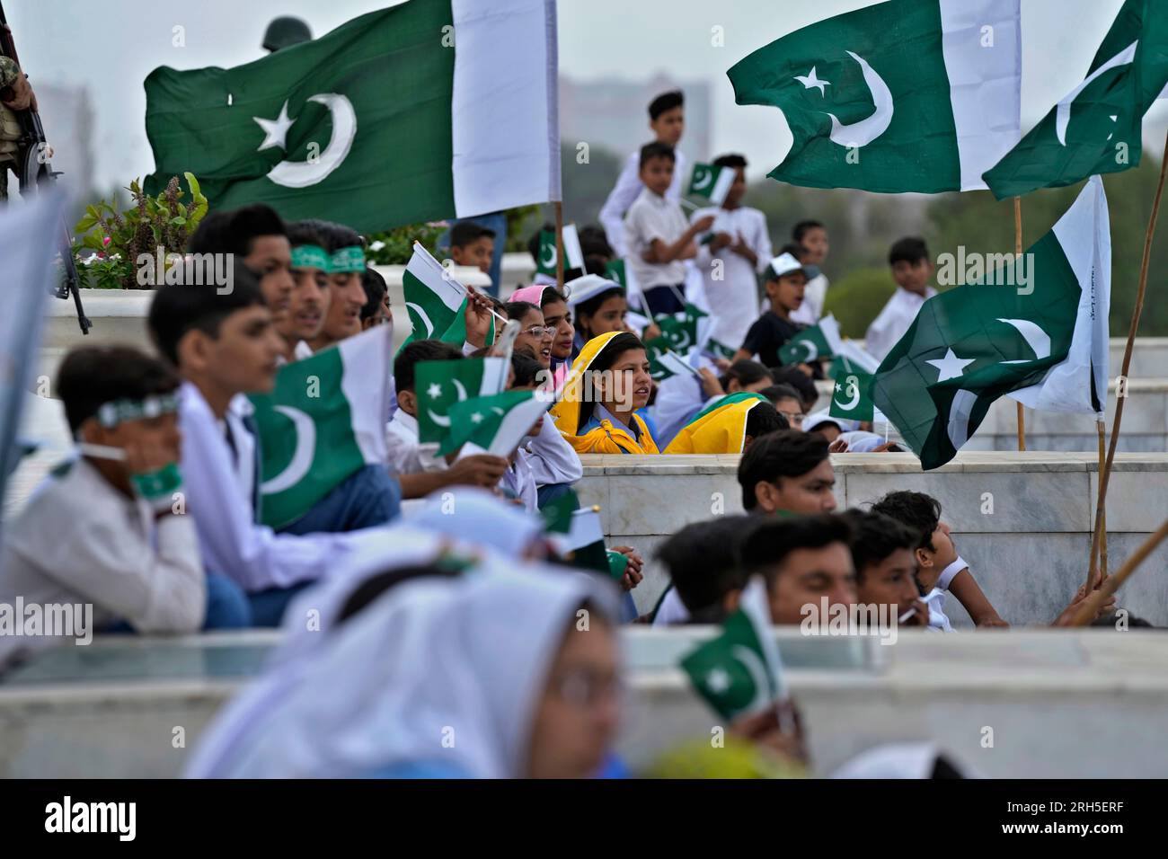 Students wave national flags during a ceremony to commemorate ...