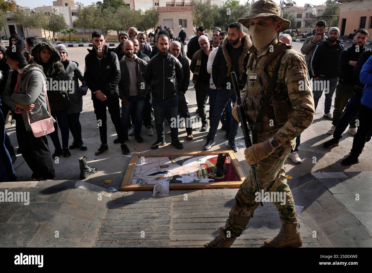 A Syrian fighter, foreground, stands guard as members of ousted Syrian ...