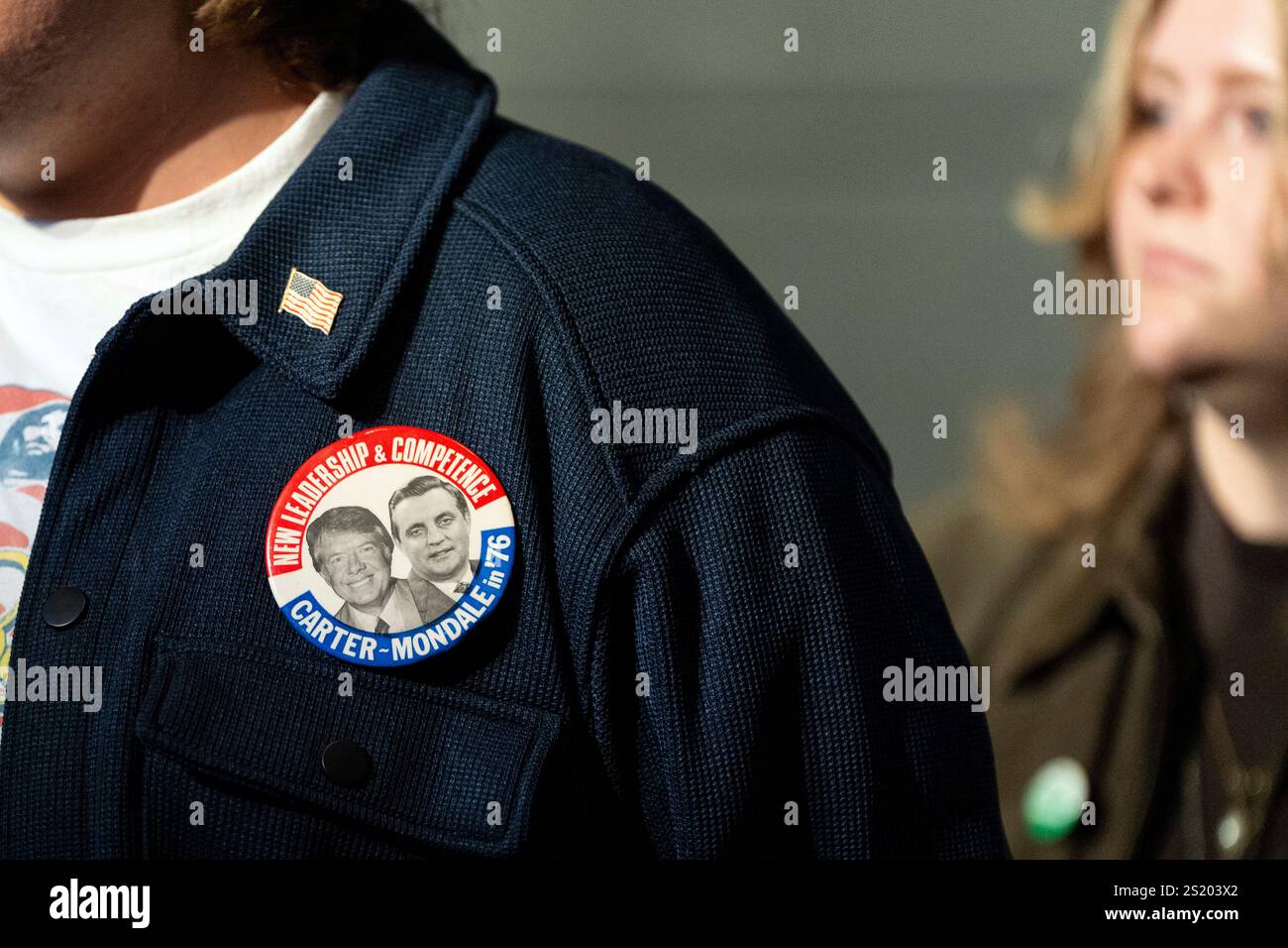A mourner wears a Carter-Mondale button as he views the casket of ...