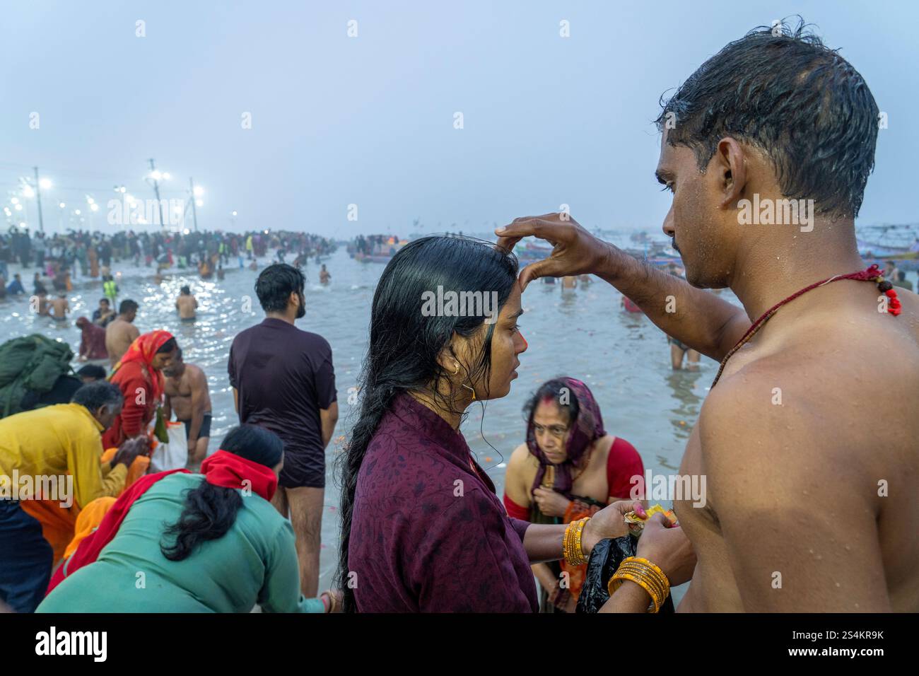 A Hindu devotee puts a vermillion mark on the forehead of his wife ...