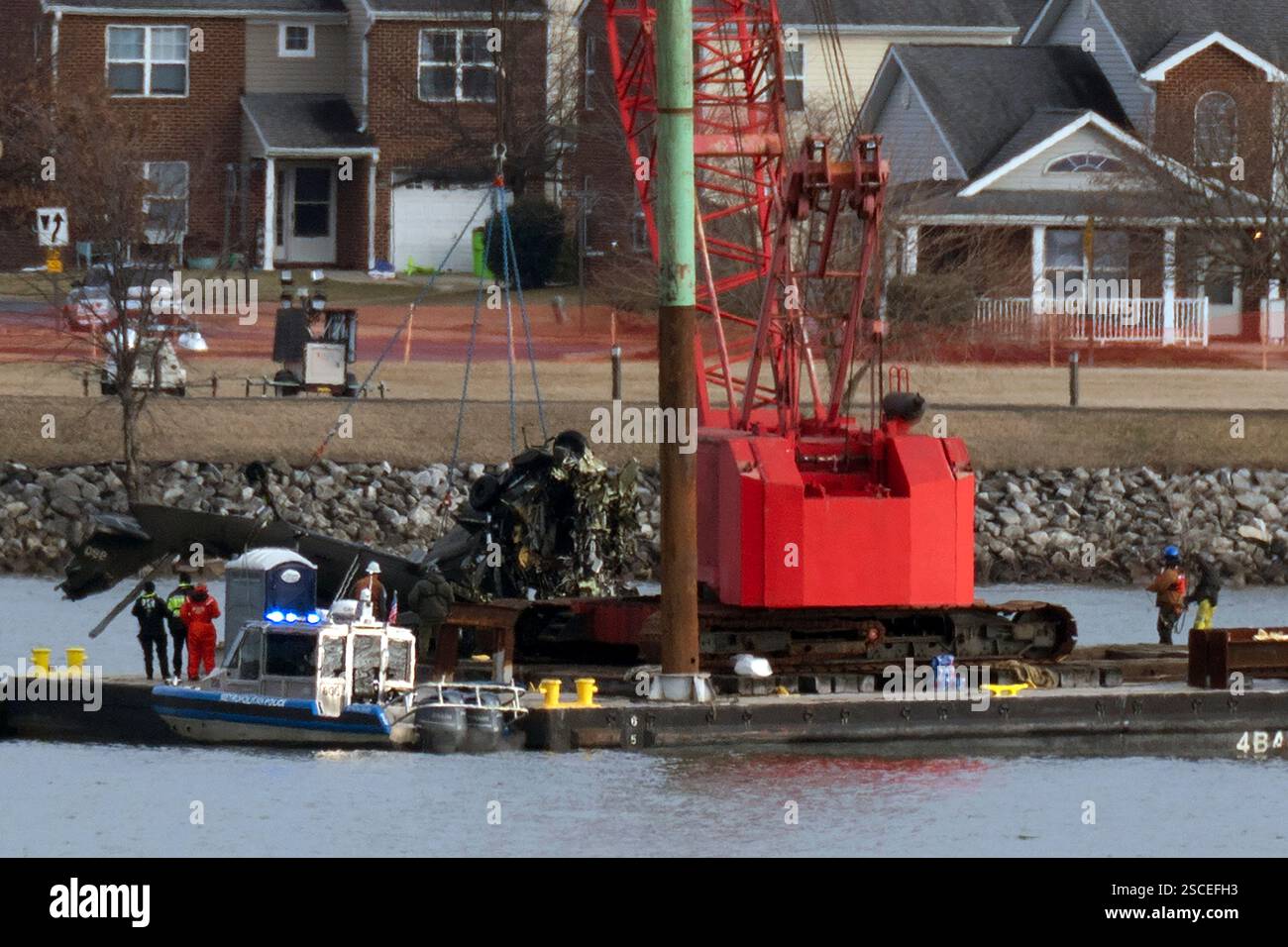 Rescue and salvage crews pull up a part of a Army Black Hawk helicopter ...