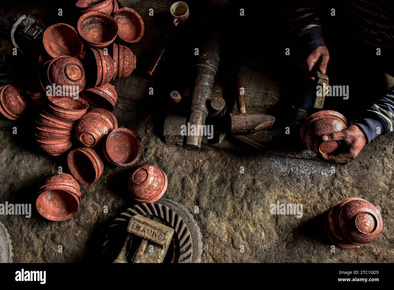 Un fabbro Kashmiri lavora su una ciotola di rame in un laboratorio. L ...