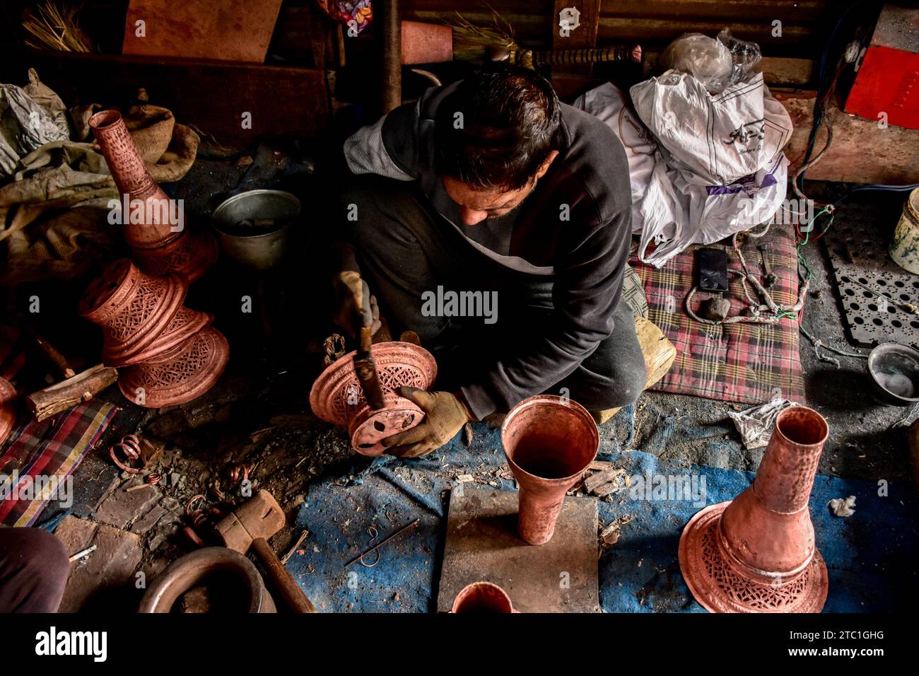 Un fabbro Kashmiri lavora su utensili in rame in un laboratorio. L ...