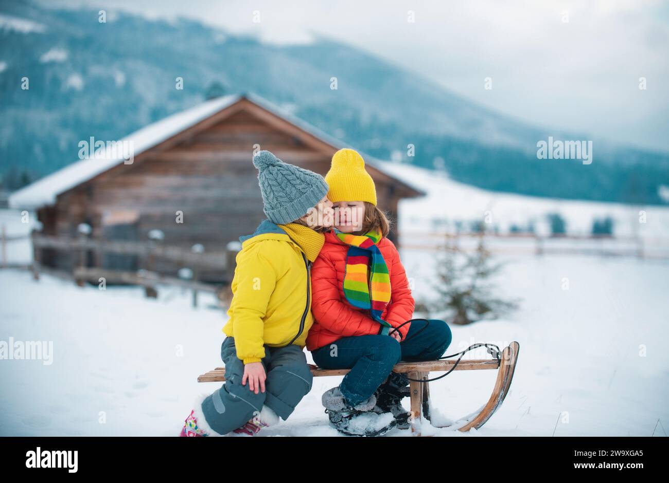 Baciare i bambini. Bambini piccoli felici e slittino in inverno. I ...