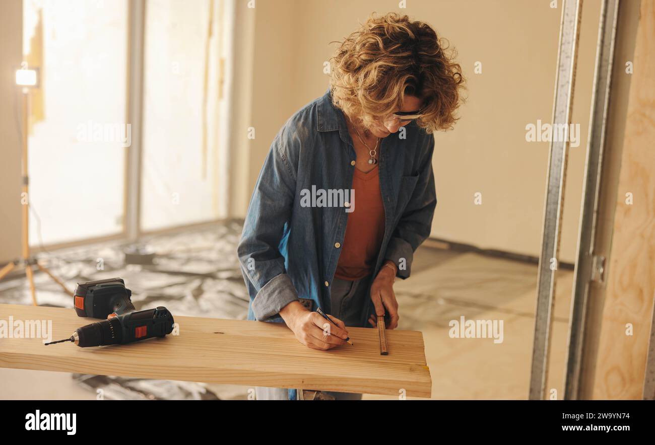 La proprietaria di una casa fai da te, una donna matura, misura la baita nella sua cucina per un ...