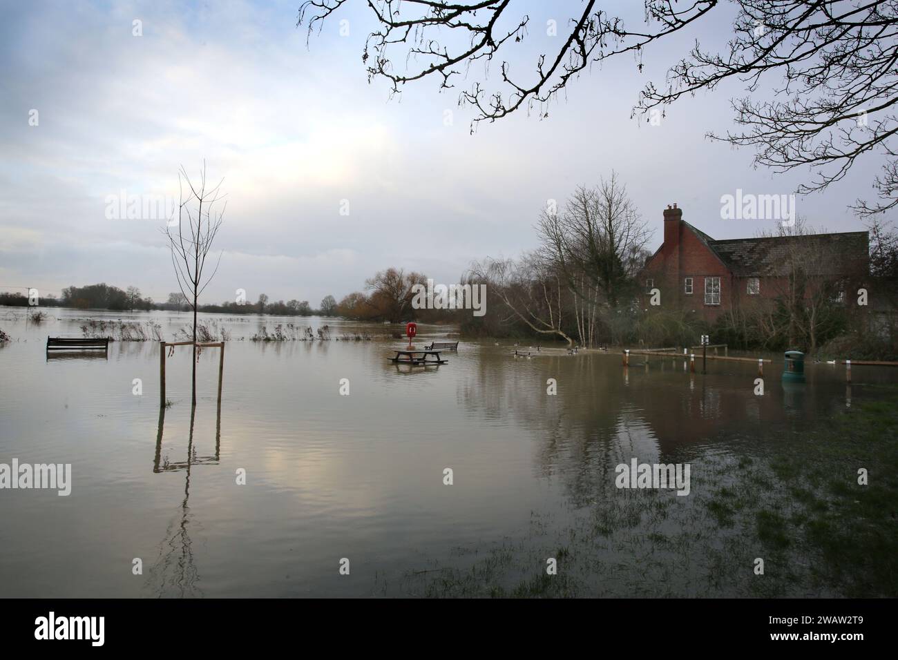 Huntingdon, Regno Unito. 6 gennaio 2024. L'acqua copre un parcheggio e un sentiero e circonda ...