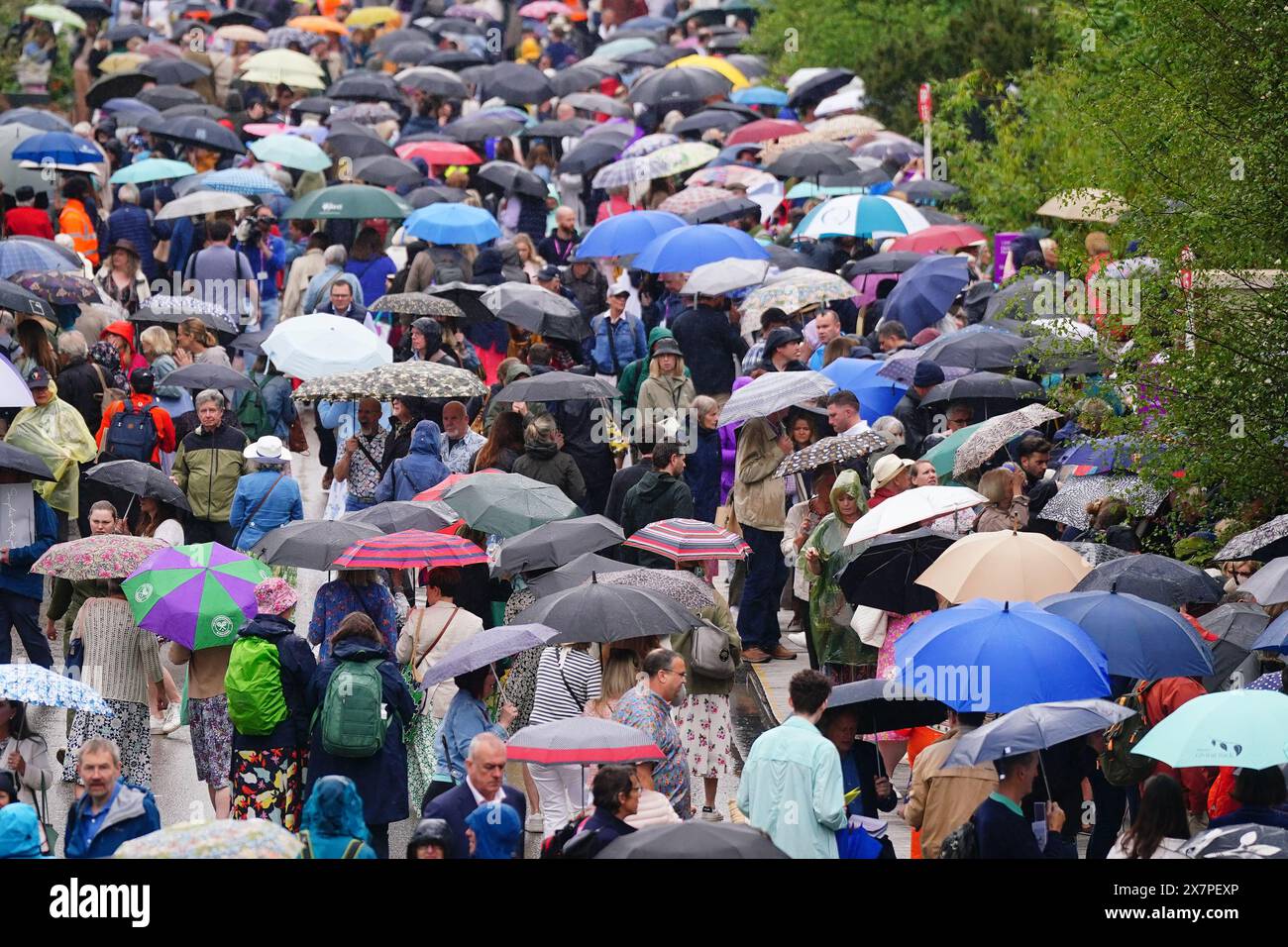 Gli ospiti si riparano sotto gli ombrelli mentre piove durante lo ...