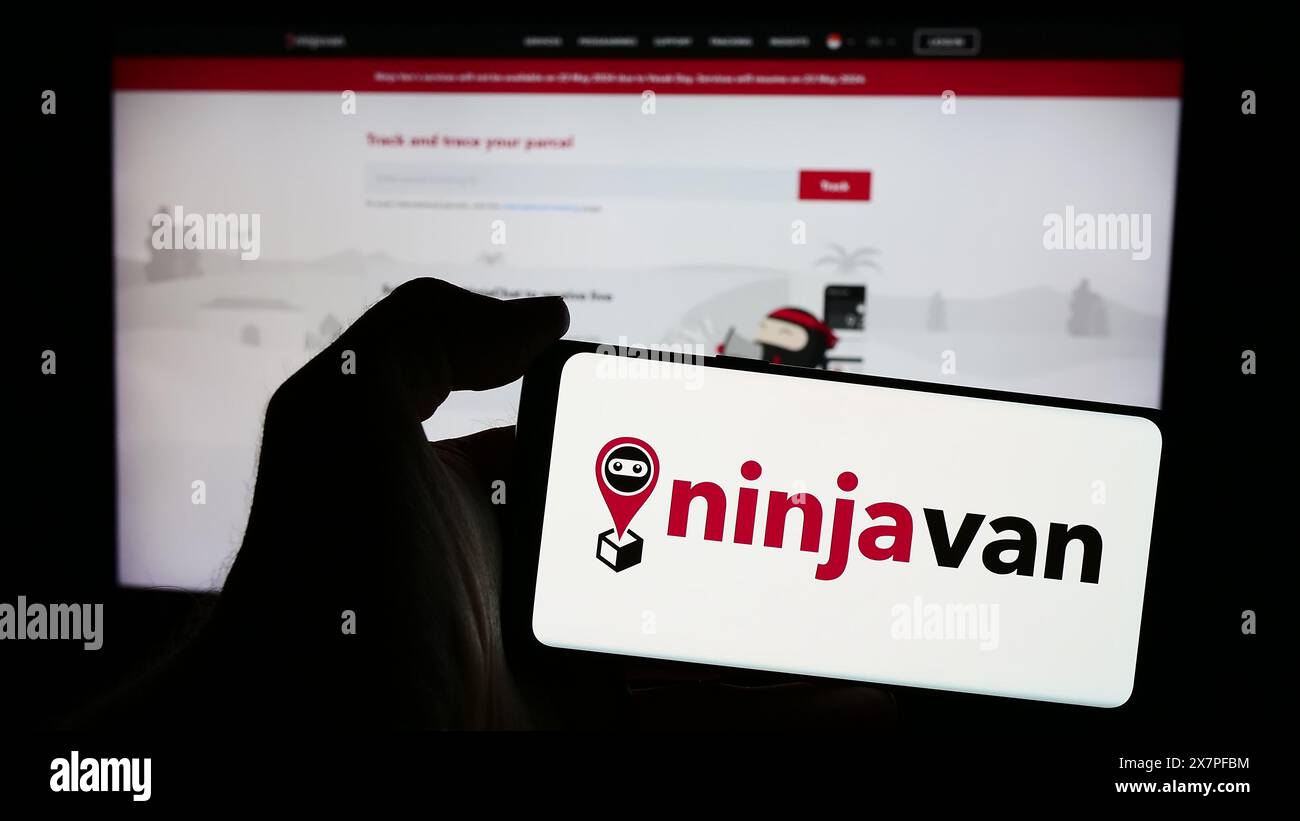 Persona che possiede un telefono cellulare con il logo della società di consegna di Singapore ...