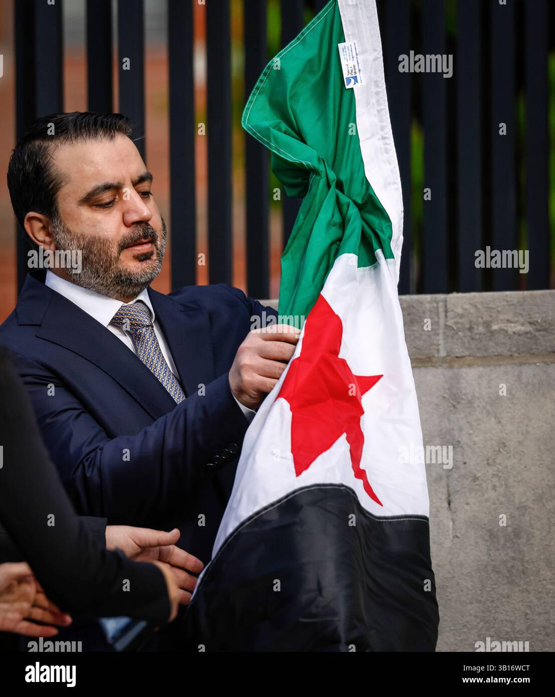 Syria's Foreign Minister Asaad Al-Shibani unfolds the Syrian Flag ...