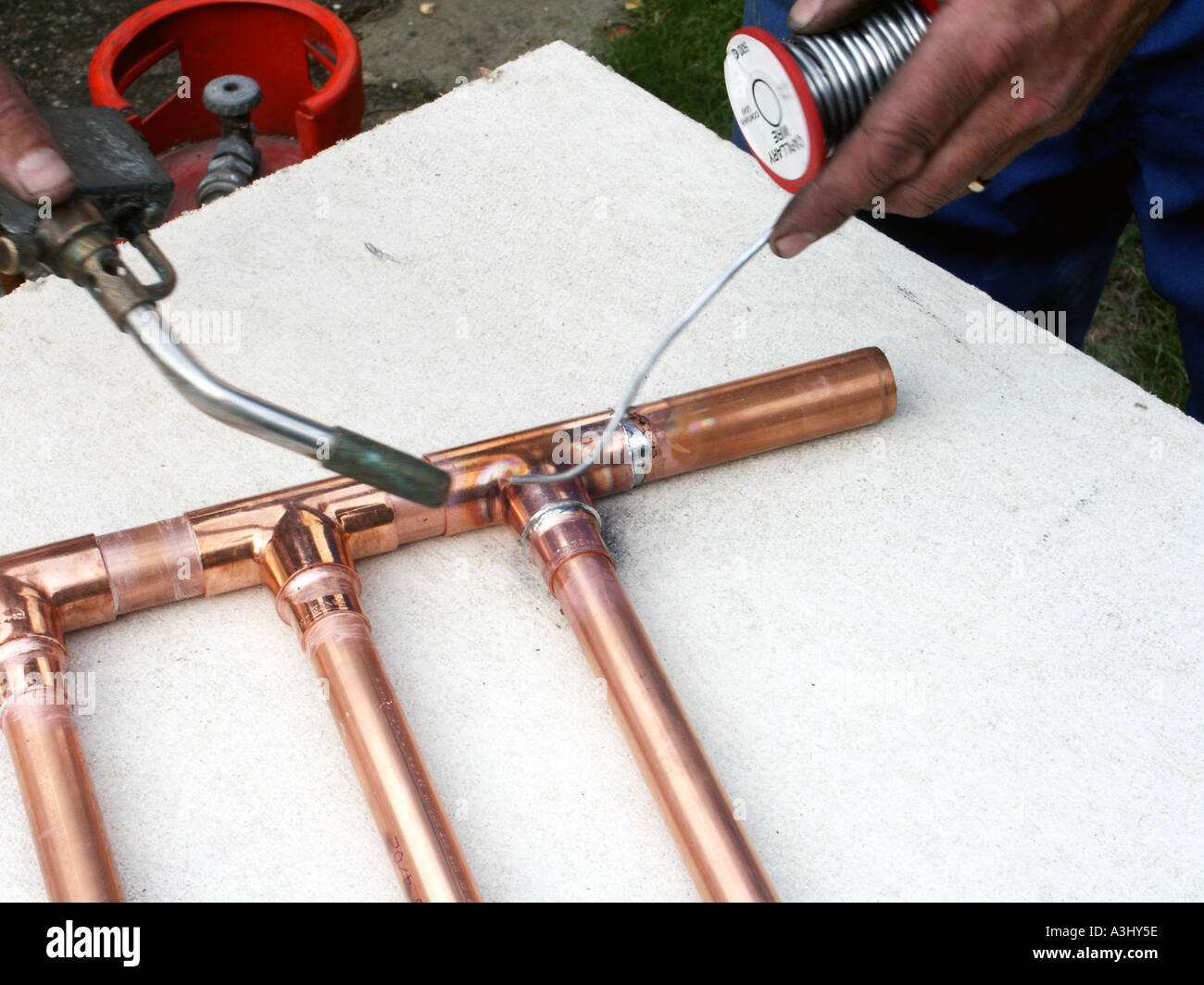 Close up idraulico utilizzando un gas propano cannello per saldatura di calore per rendere un ...