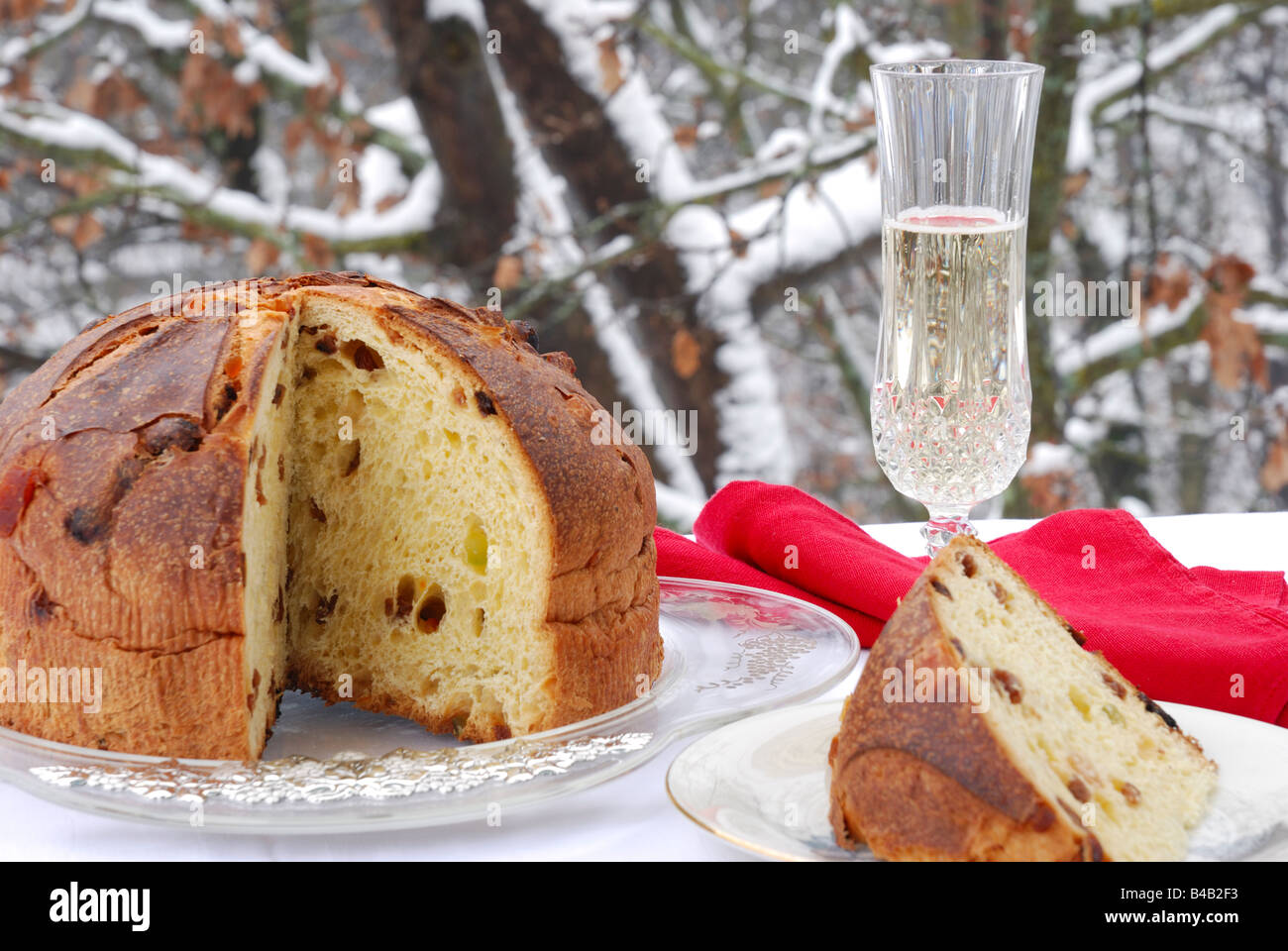 Panettone natalizio con un bicchiere di prosecco e neve in background ...