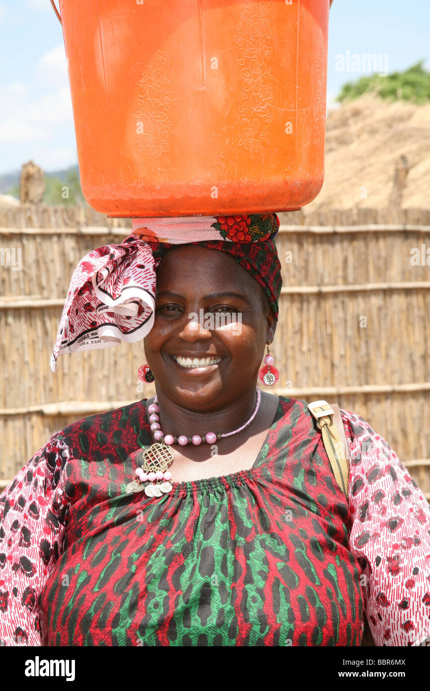 Una donna africana che porta un secchio di acqua sulla sua testa ...