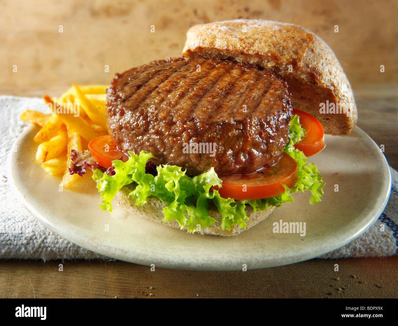 Hamburger di manzo in un panino integrale con insalata e patatine ...