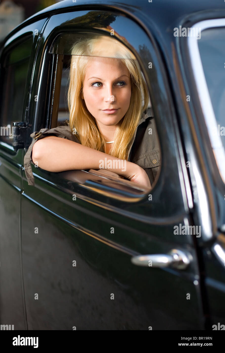 Giovane e bella ragazza bionda in posa con nero auto d'epoca Foto stock ...