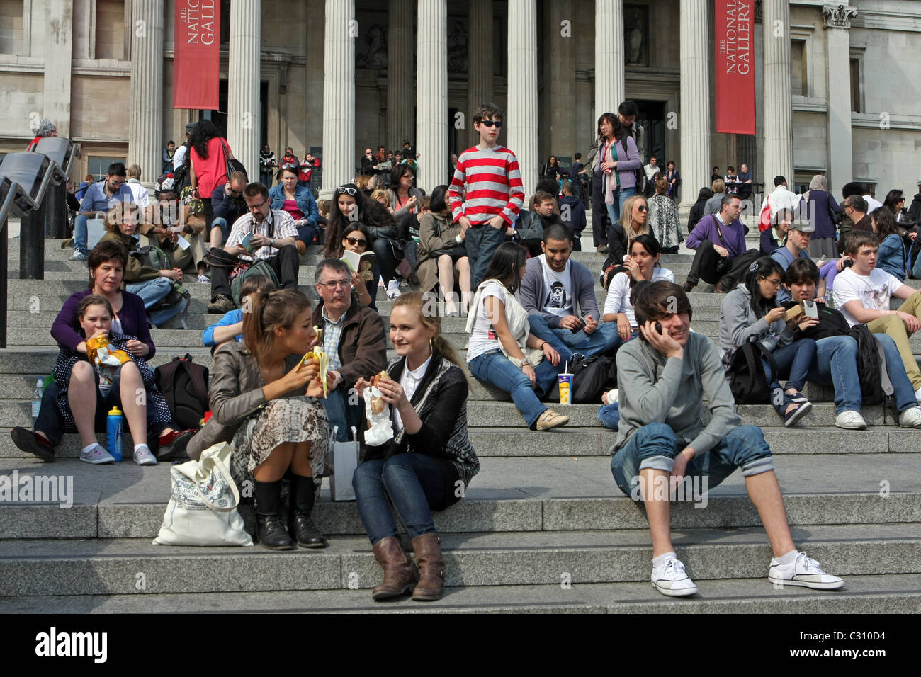 Gruppi di persone sedute sui gradini di Trafalgar Square a Londra ...