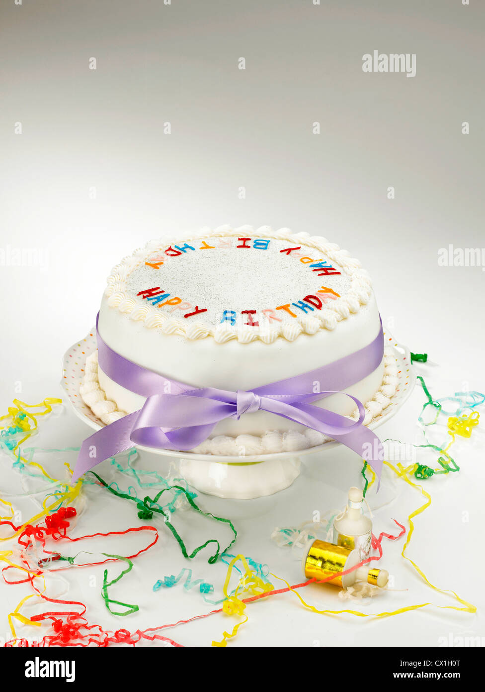 Un bianco torta di compleanno sulla torta stand con party streamers ...