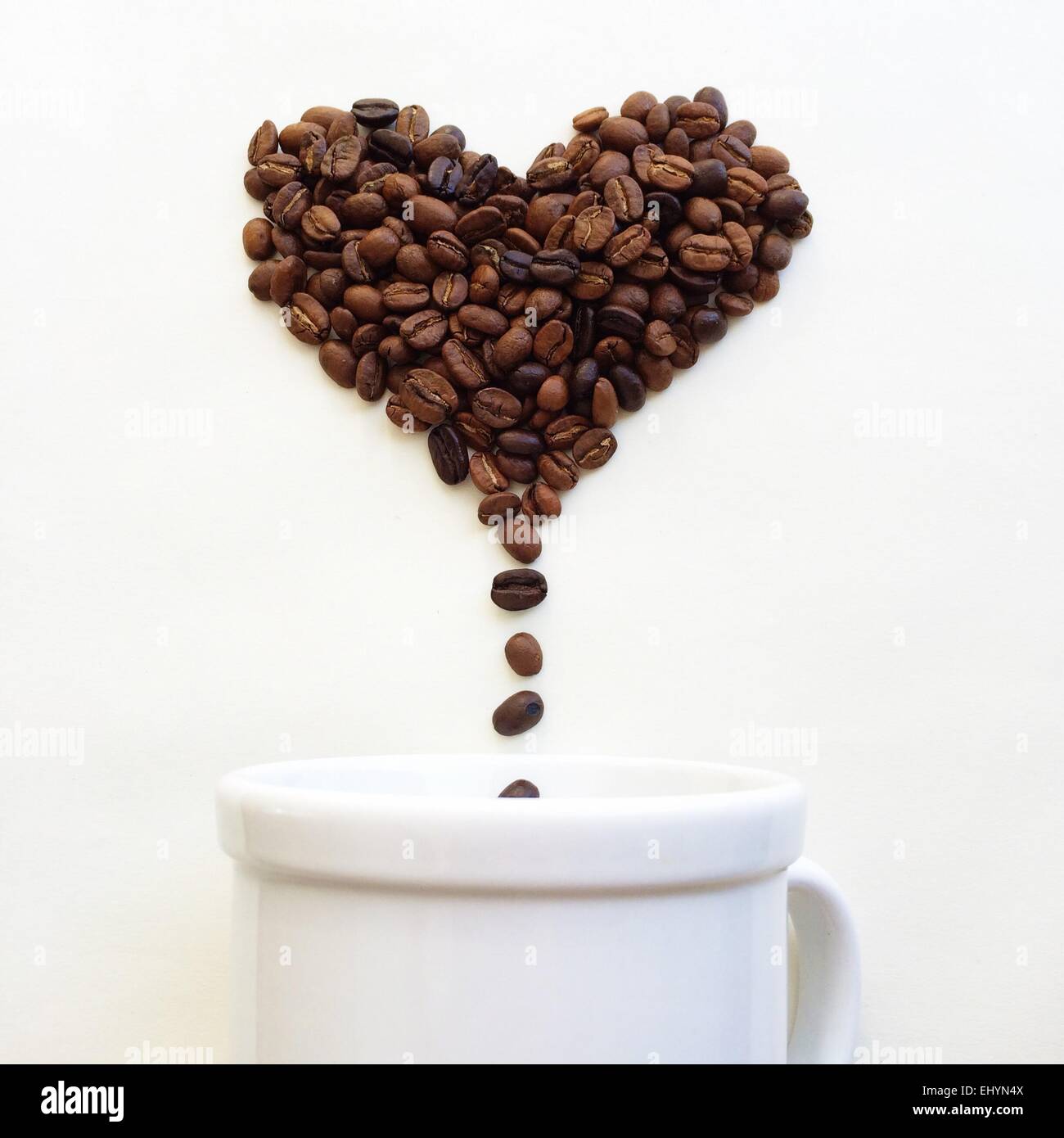 I chicchi di caffè in forma di cuore che cade in una tazza di caffè ...