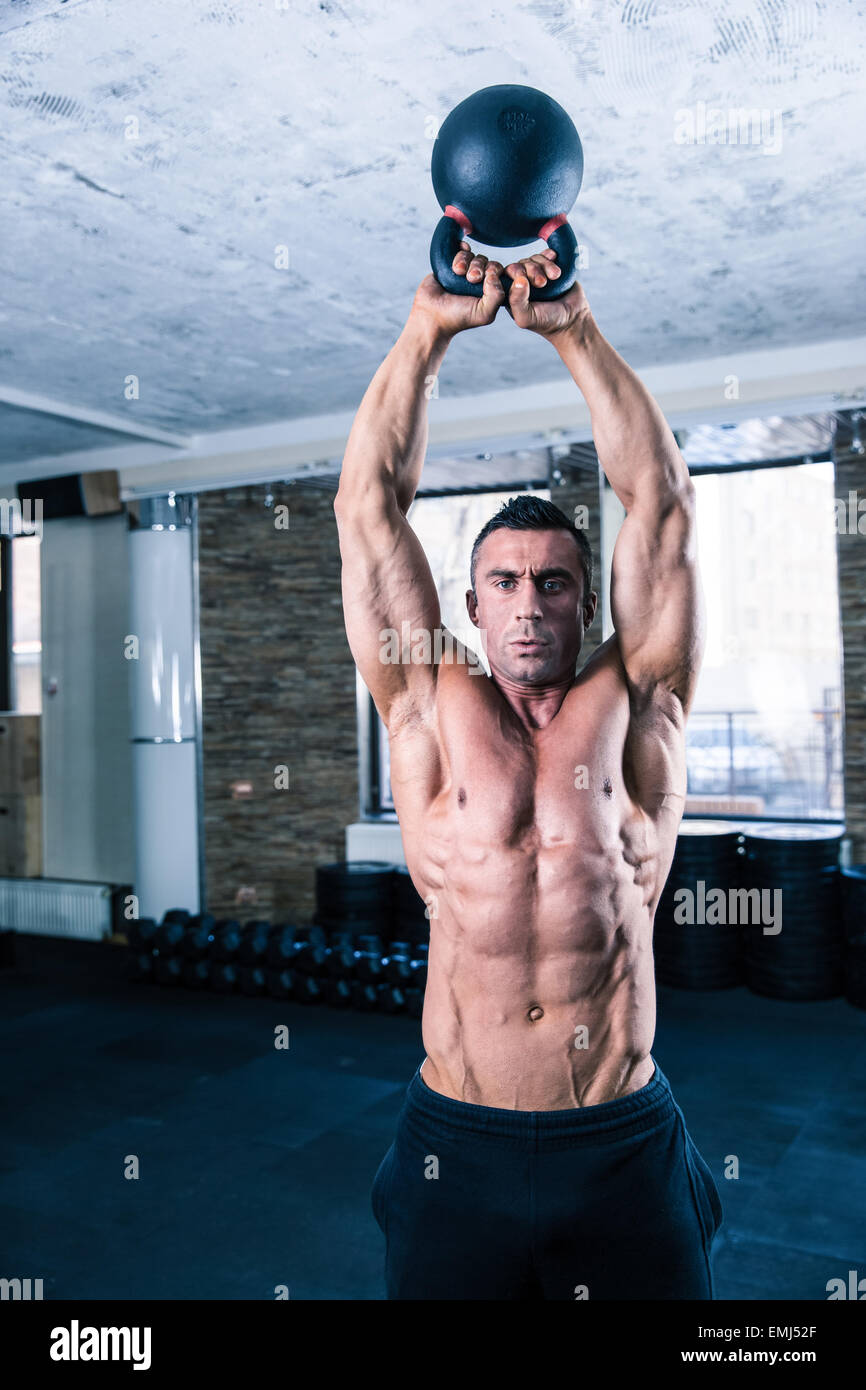 Bel culturista uomo allenamento con bollitore palla in palestra ...