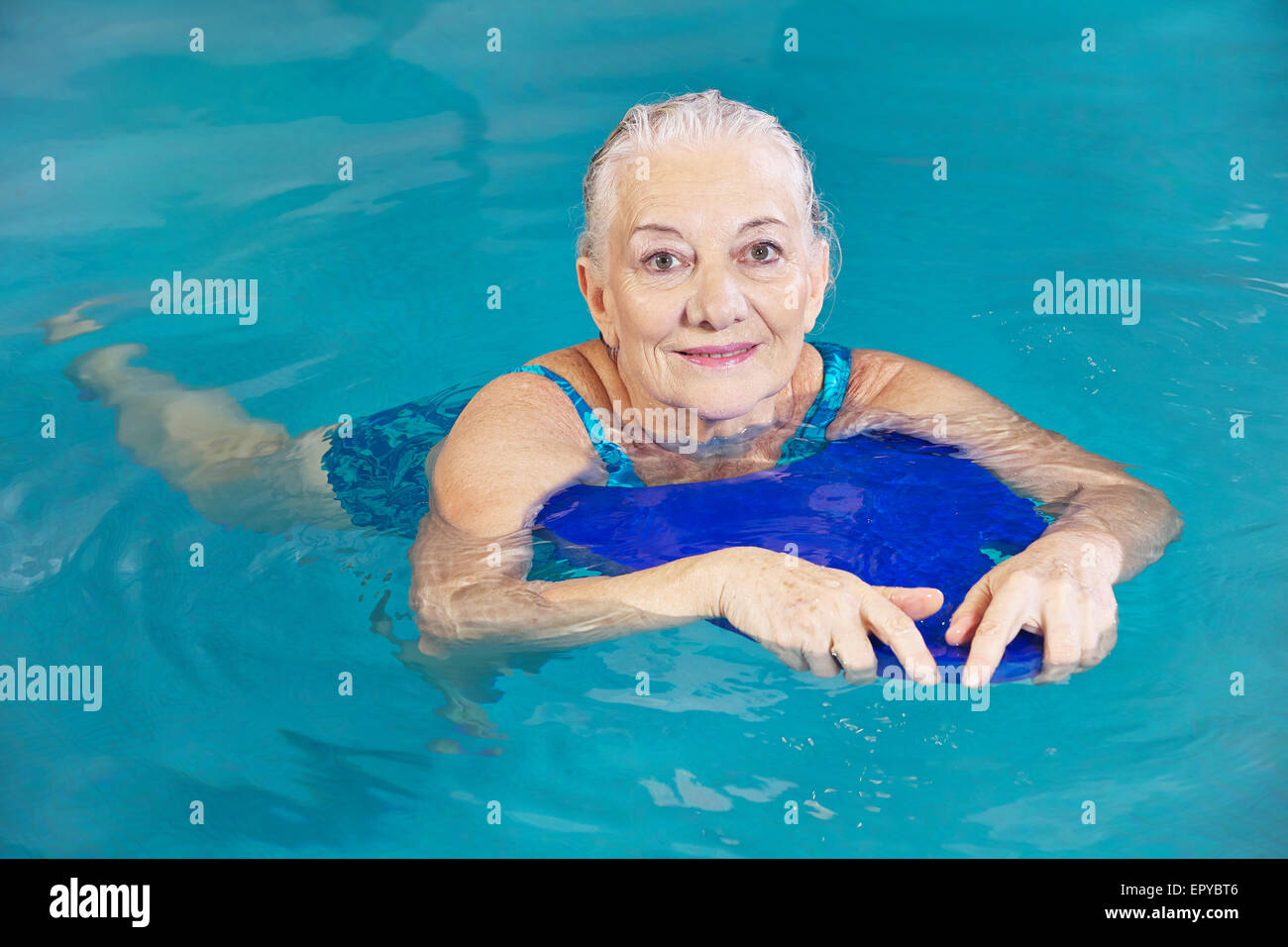 Vecchia donna nuotare in acqua con kickboard nella piscina di un hotel ...