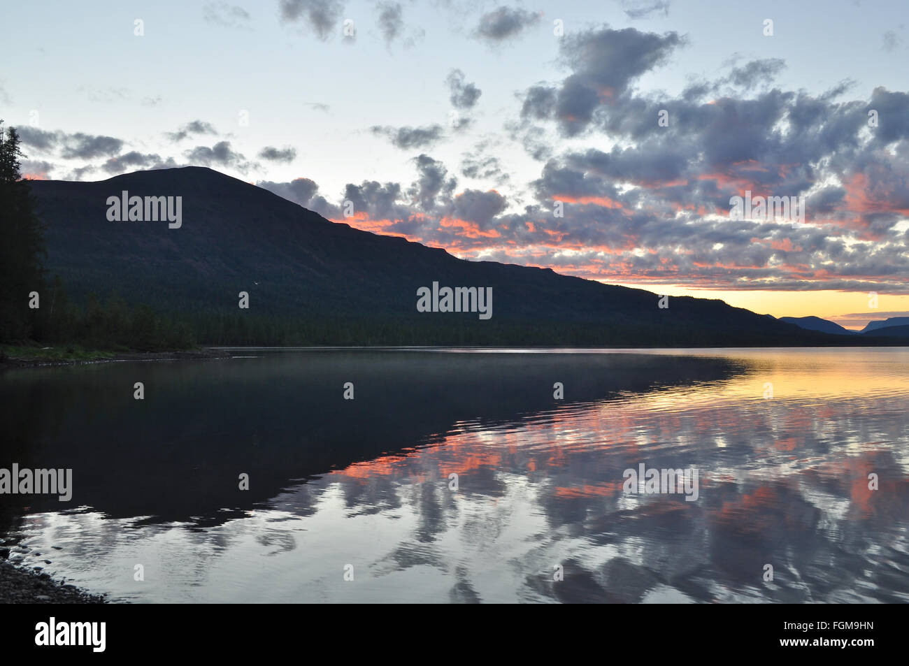 Alba sul lago. Rosa nuvole dipinte dal sorgere del sole riflessa nelle ...