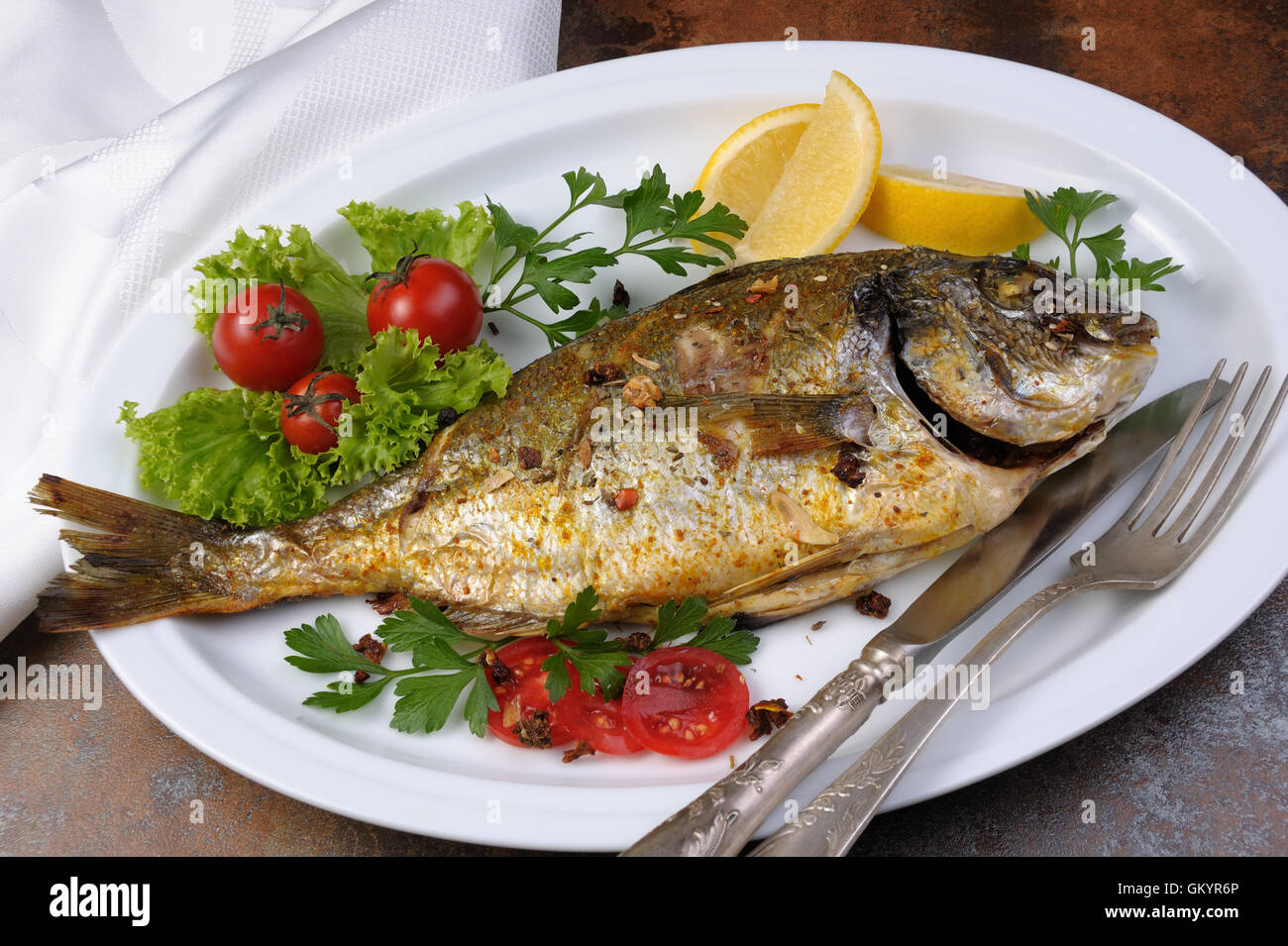 Pesce arrosto Dorado con verdure guarnire e le fette di limone su una ...