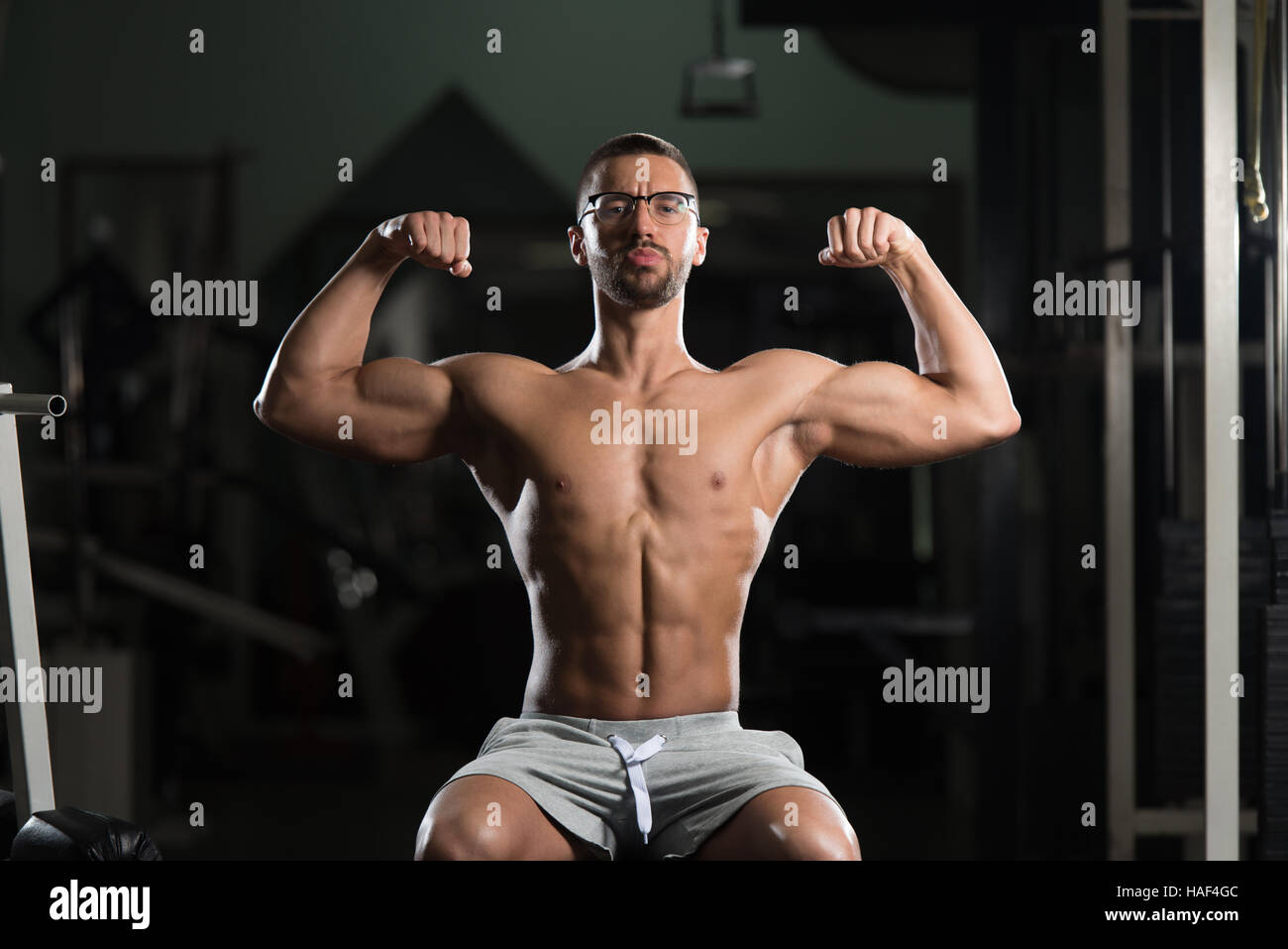 Ritratto di un giovane fisicamente Nerd uomo che mostra il suo ben ...