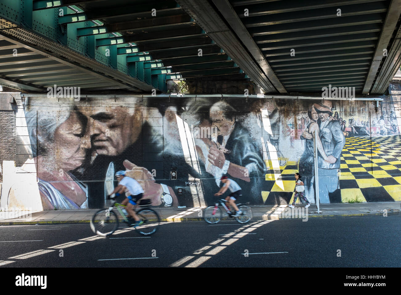 I ciclisti e i pedoni viaggiano sotto un ponte ferroviario dove muri ...