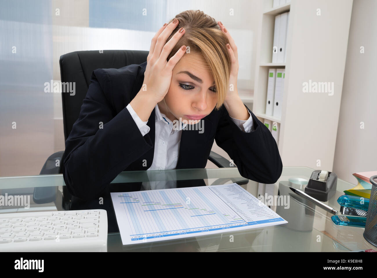 Ritratto di sottolineato imprenditrice seduto alla scrivania con ...