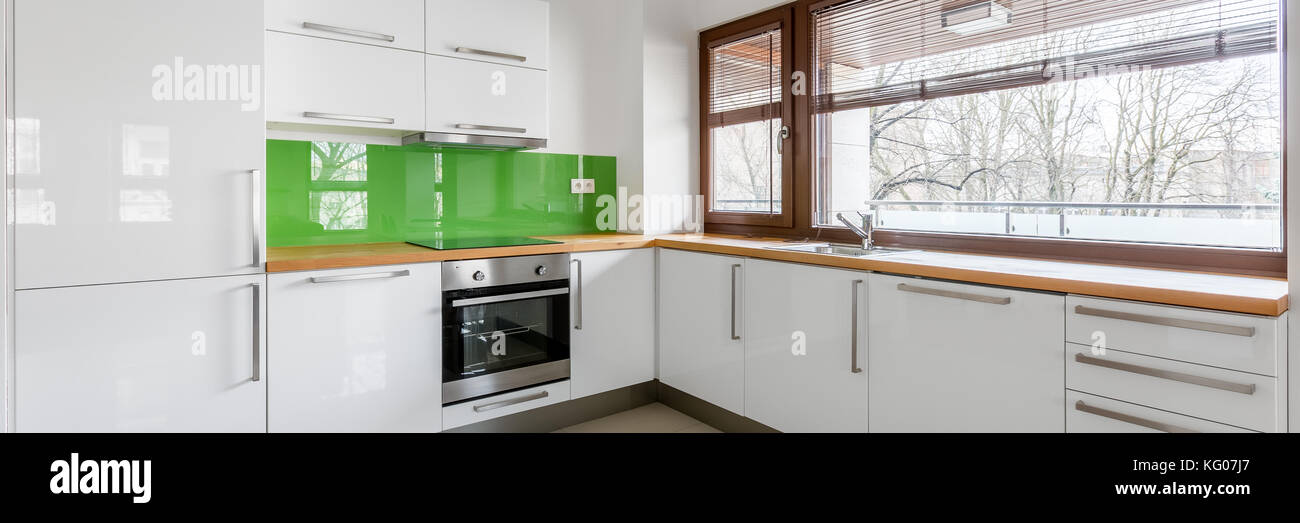 Moderna cucina bianca con sfondo verde e finestra lunga, panorama Foto ...