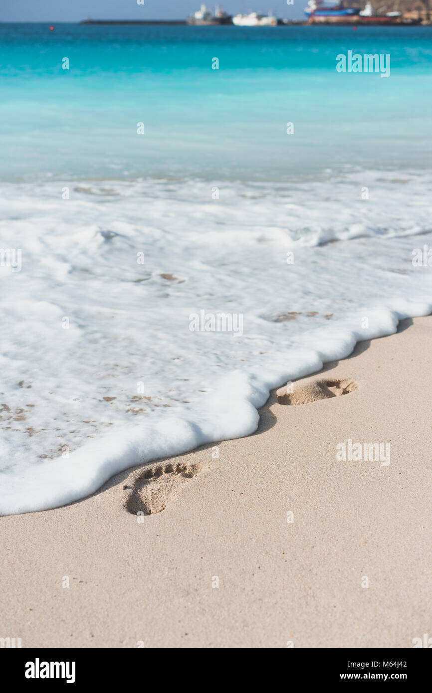 Le onde del mare toccando il piede le stampe sulla spiaggia tropicale ...
