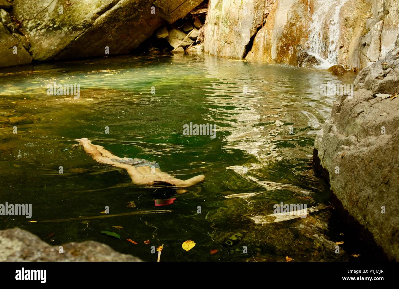 Giovane uomo che nuota sott'acqua in una piscina tropicale di montagna ...
