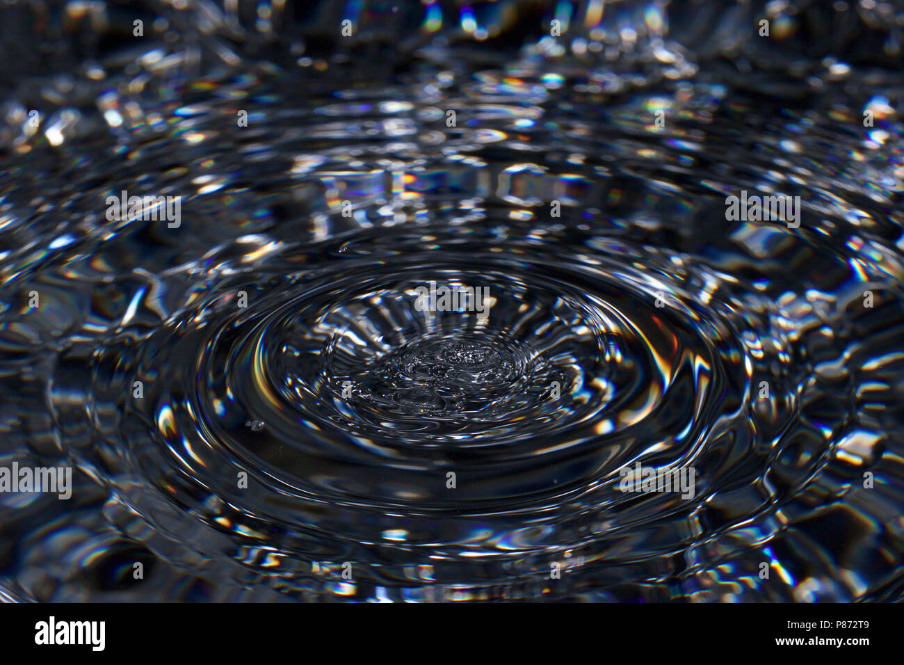 Le goccioline di acqua caduta in acqua causando gli spruzzi e le ...