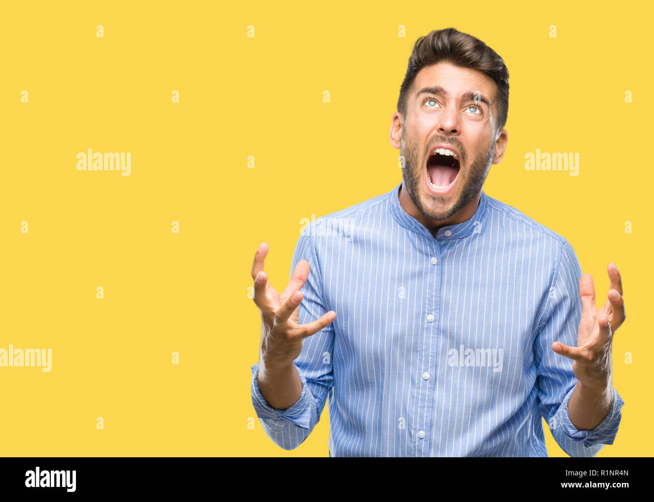 Giovane uomo bello su sfondo isolato e pazzo pazzo grida e urla con ...