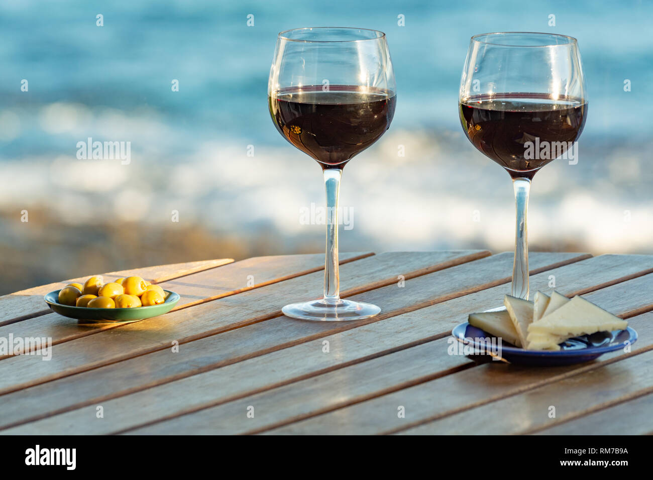 Aperitivo, vino rosso in bicchieri servito con il formaggio e le olive ...