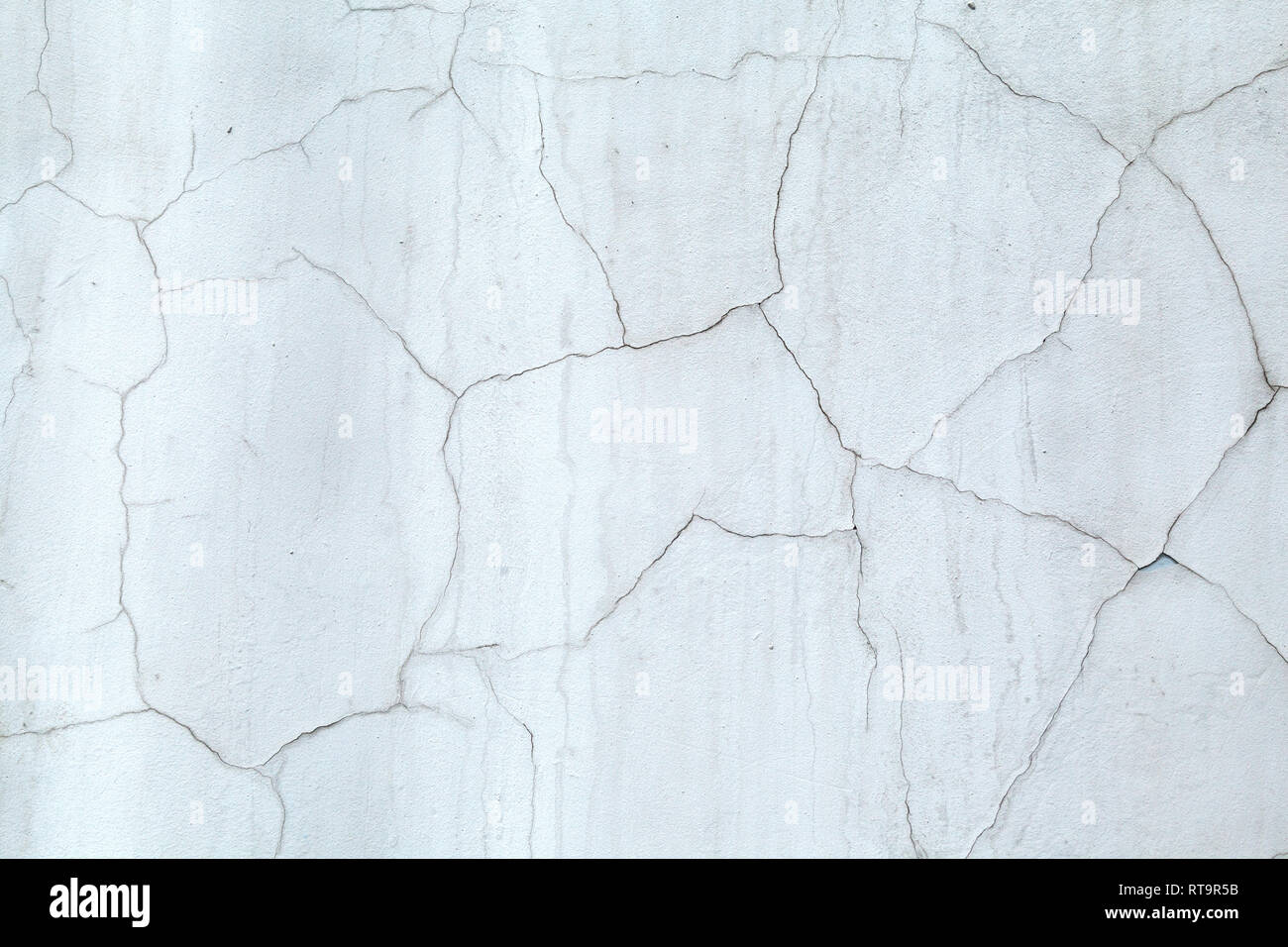 Grigio vecchio muro di cemento rivestito con intonaco rotto. Le crepe ...