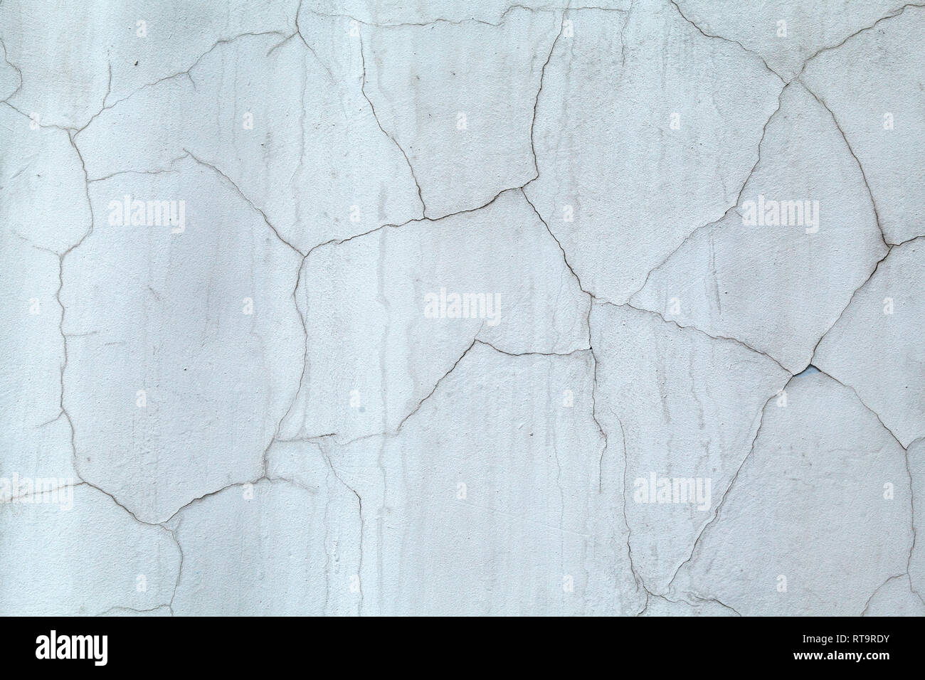 Grigio vecchio muro di cemento rivestito con intonaco rotto. Le crepe ...