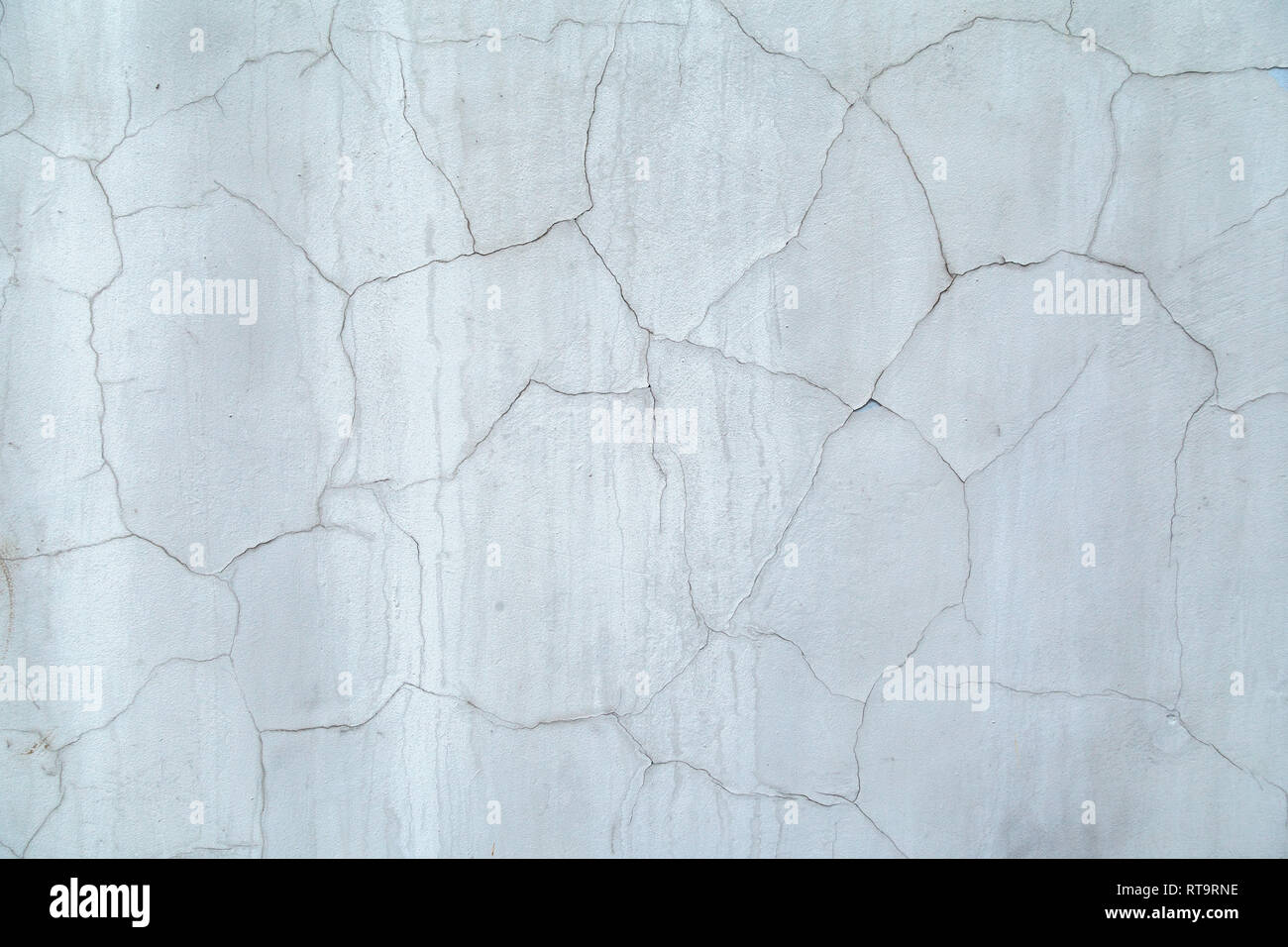 Grigio vecchio muro di cemento rivestito con intonaco rotto. Le crepe ...