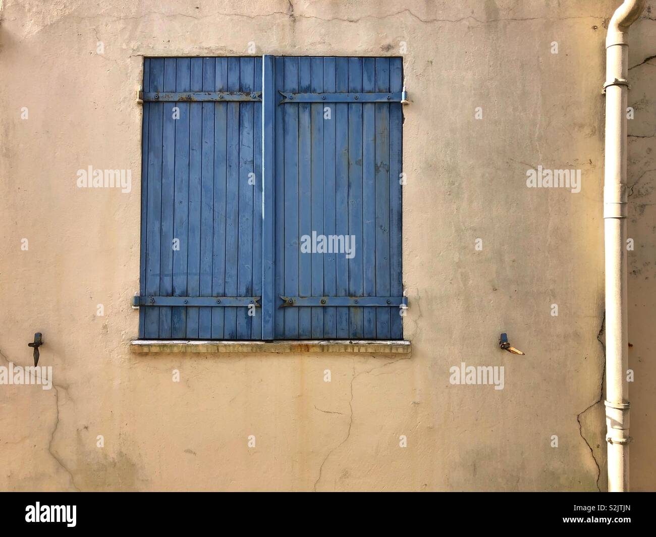 Persiane blu su un pallido giallo a parete, Francia Foto stock - Alamy