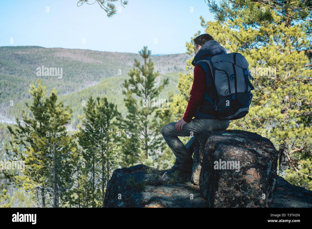 Uomo escursionista turistica con uno zaino grande seduto su una rupe di ...