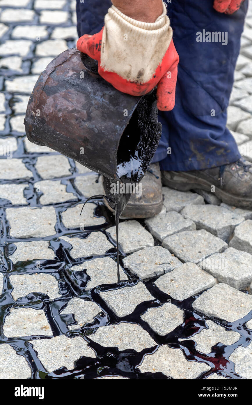Versando passo fuso da un secchio di catrame. Passo tradizionale per ...