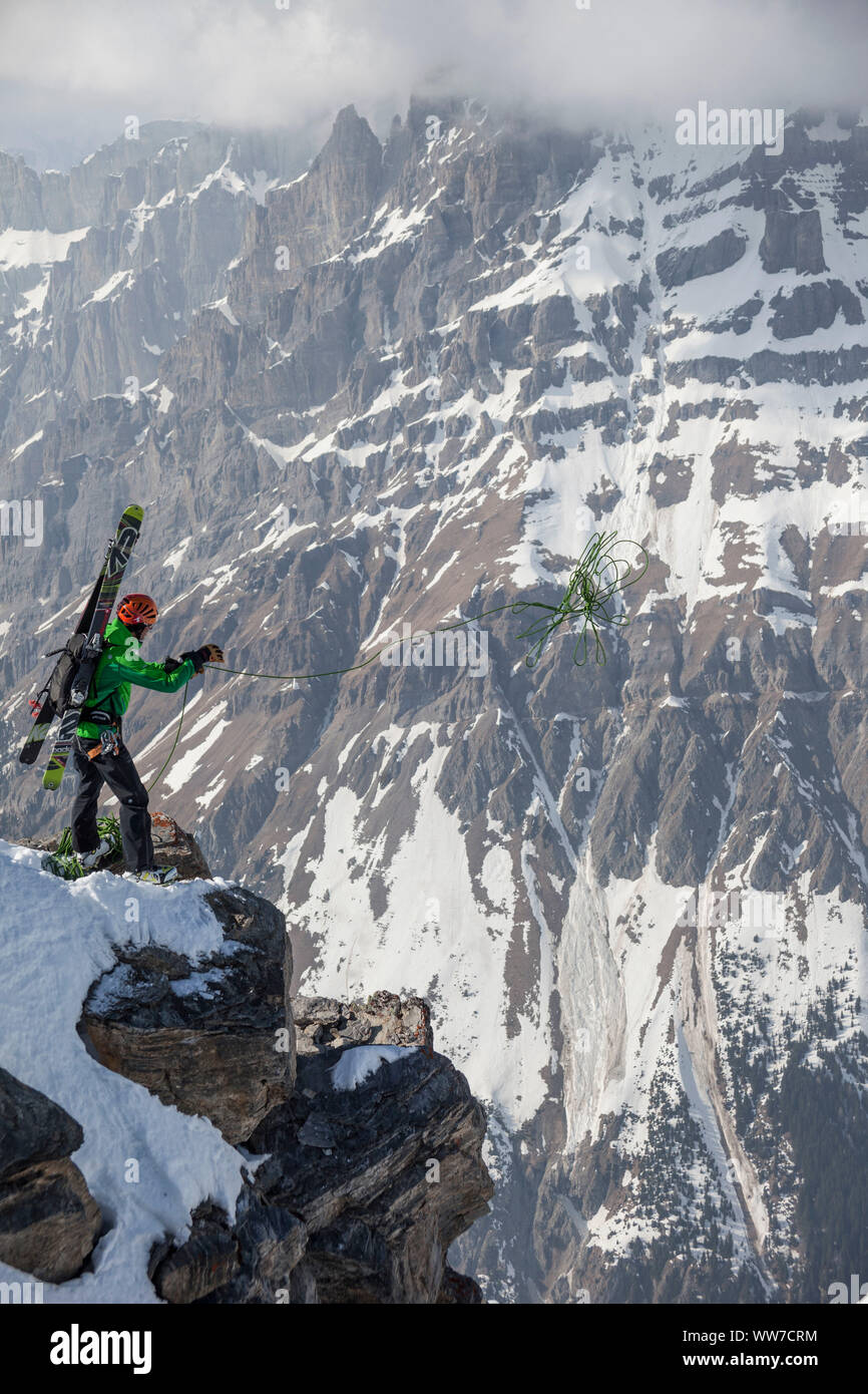 Lo scialpinista lancia la corda per la discesa in corda doppia a la ...